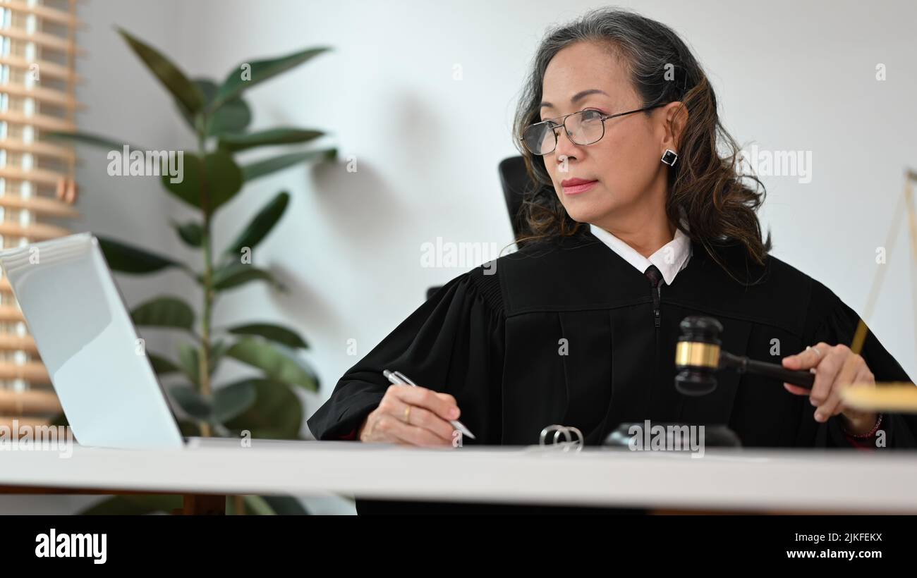 Elegant mature female judge holding gavel hammer mallet, talking to her ...