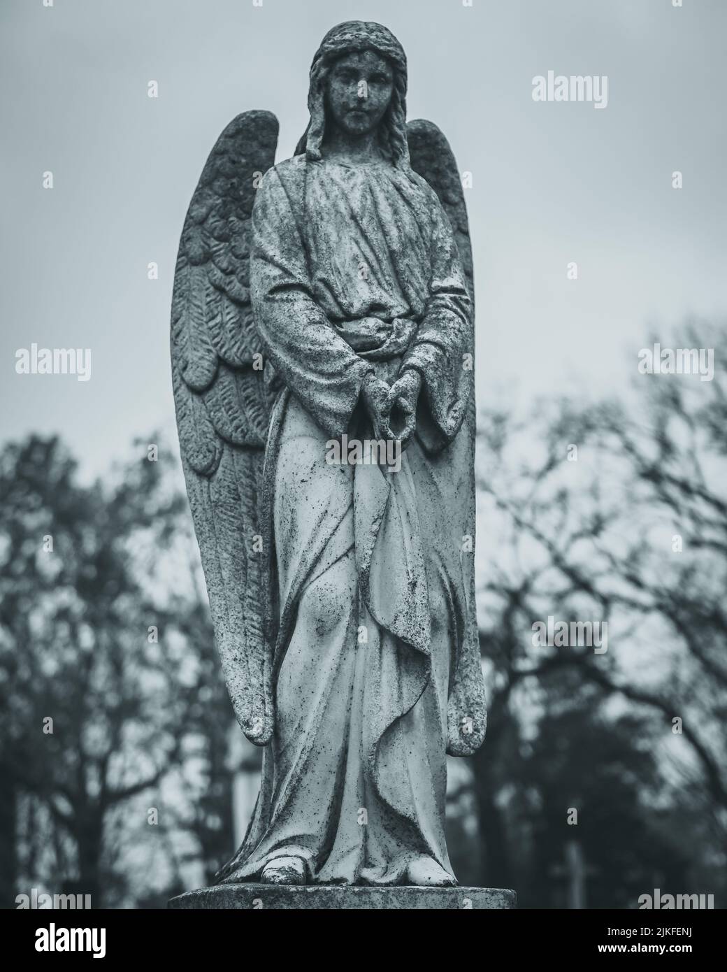 A vertical closeup of a beautiful stone sculpture of an angel in a park ...