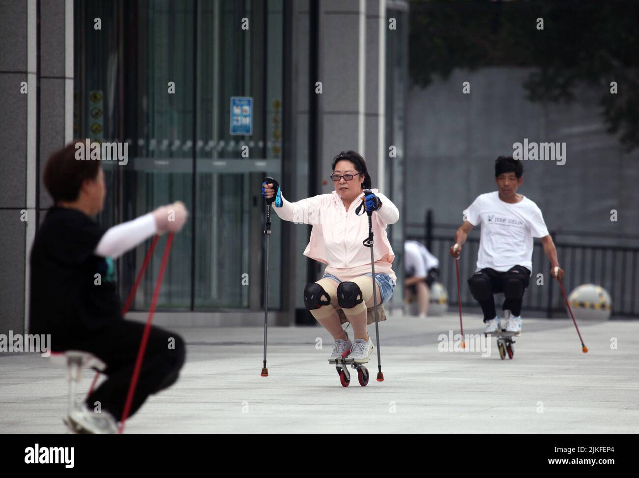 A group of retired elderly people crouch on a special roller skater ...