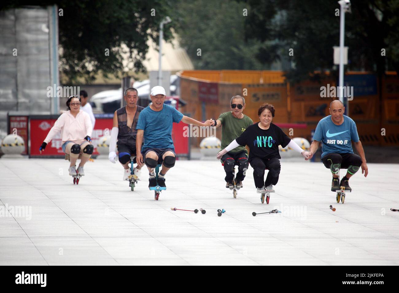 A group of retired elderly people crouch on a special roller skater ...