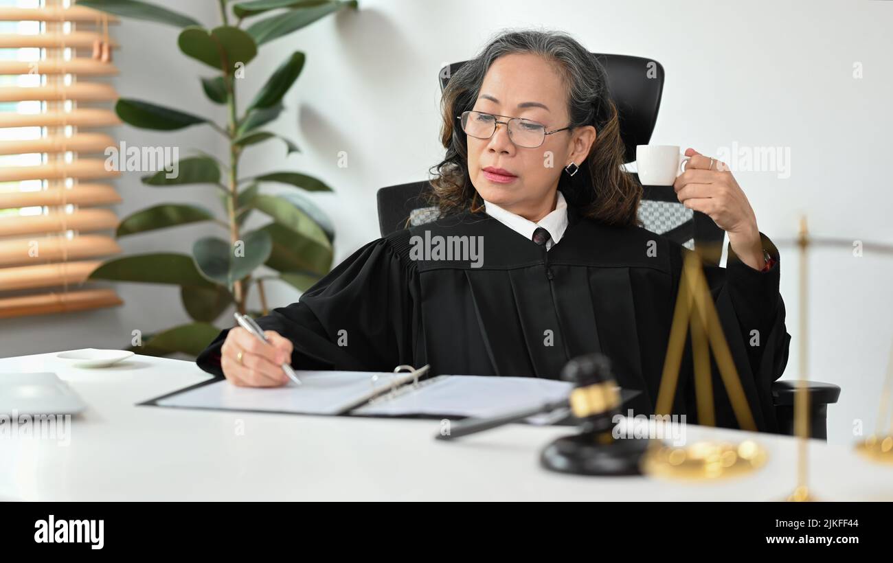 Judge, lawyer or attorney dressed in robe gown uniform working with ...