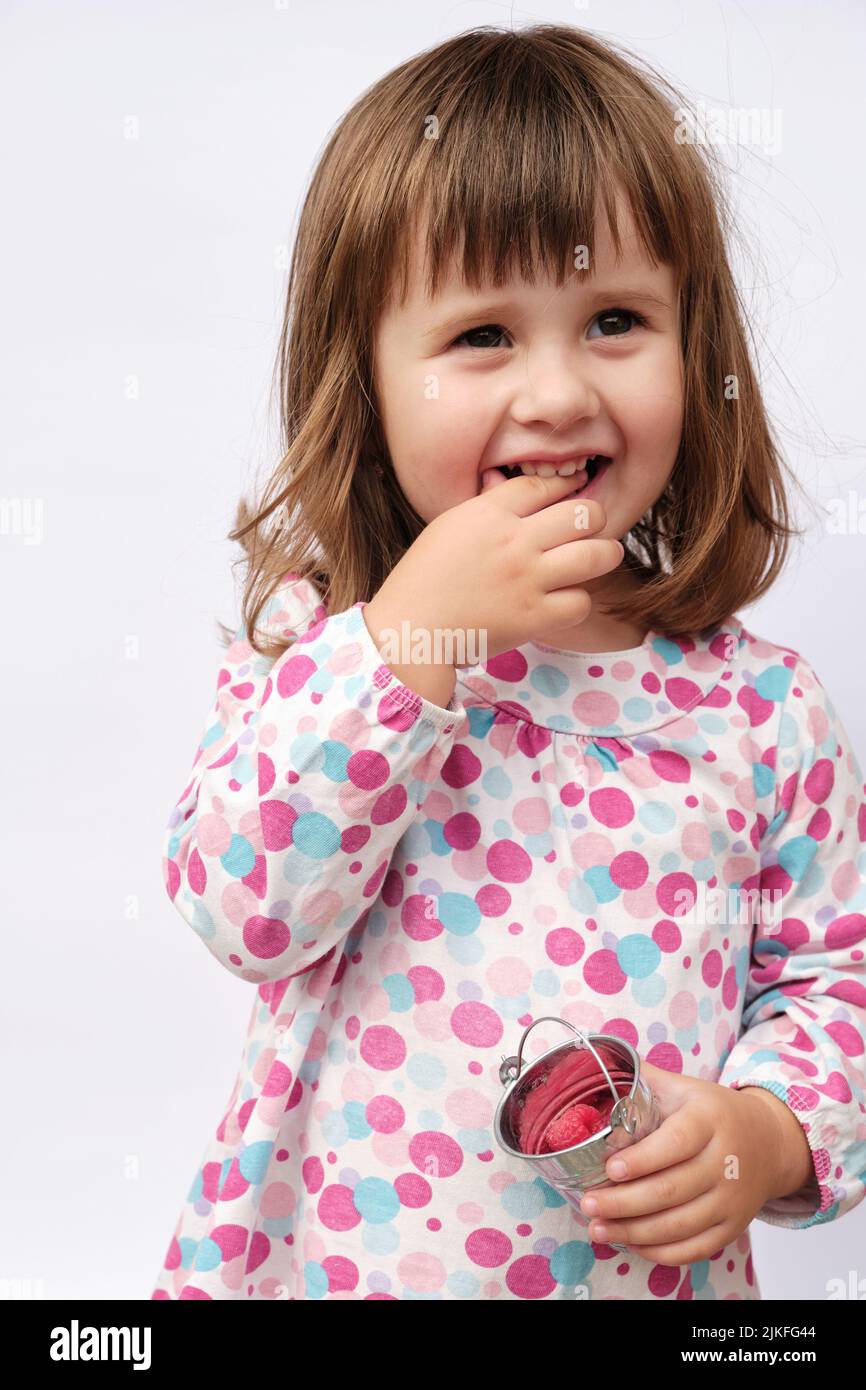 Little baby eating raspberry from decorative metal bucket. Cute little ...