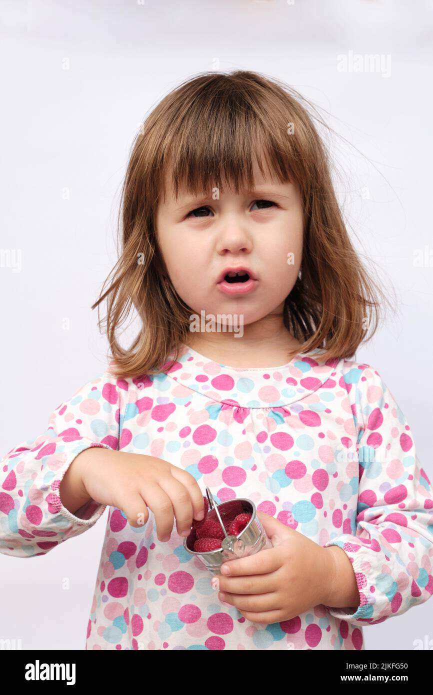 Little baby eating raspberry from decorative metal bucket. Child ...