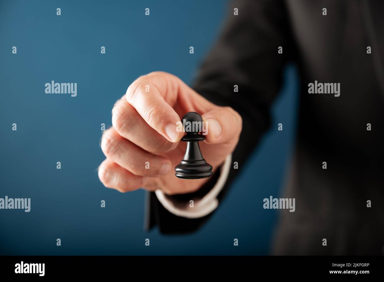 Closeup view of hand of a businessman holding black chess pawn piece ...