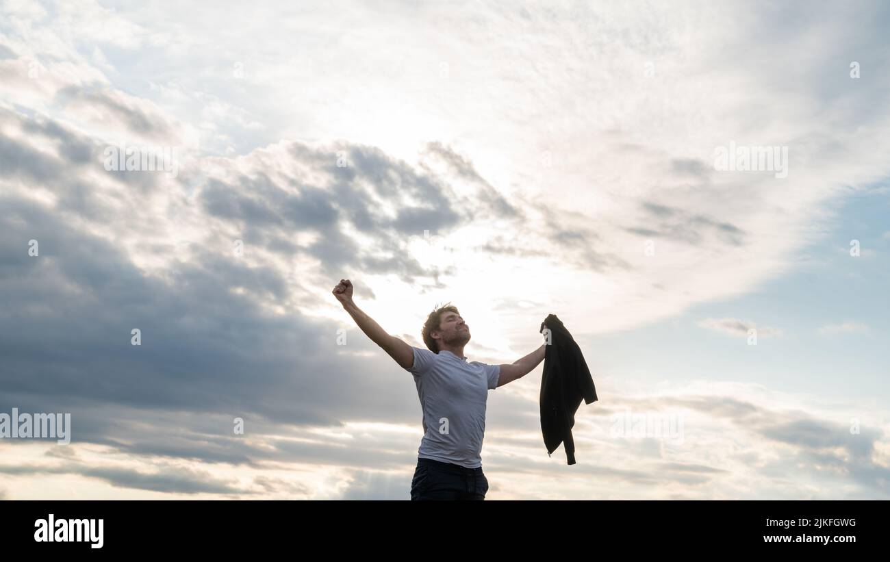 Proud young man standing under cloudy evening sky celebrating his life ...
