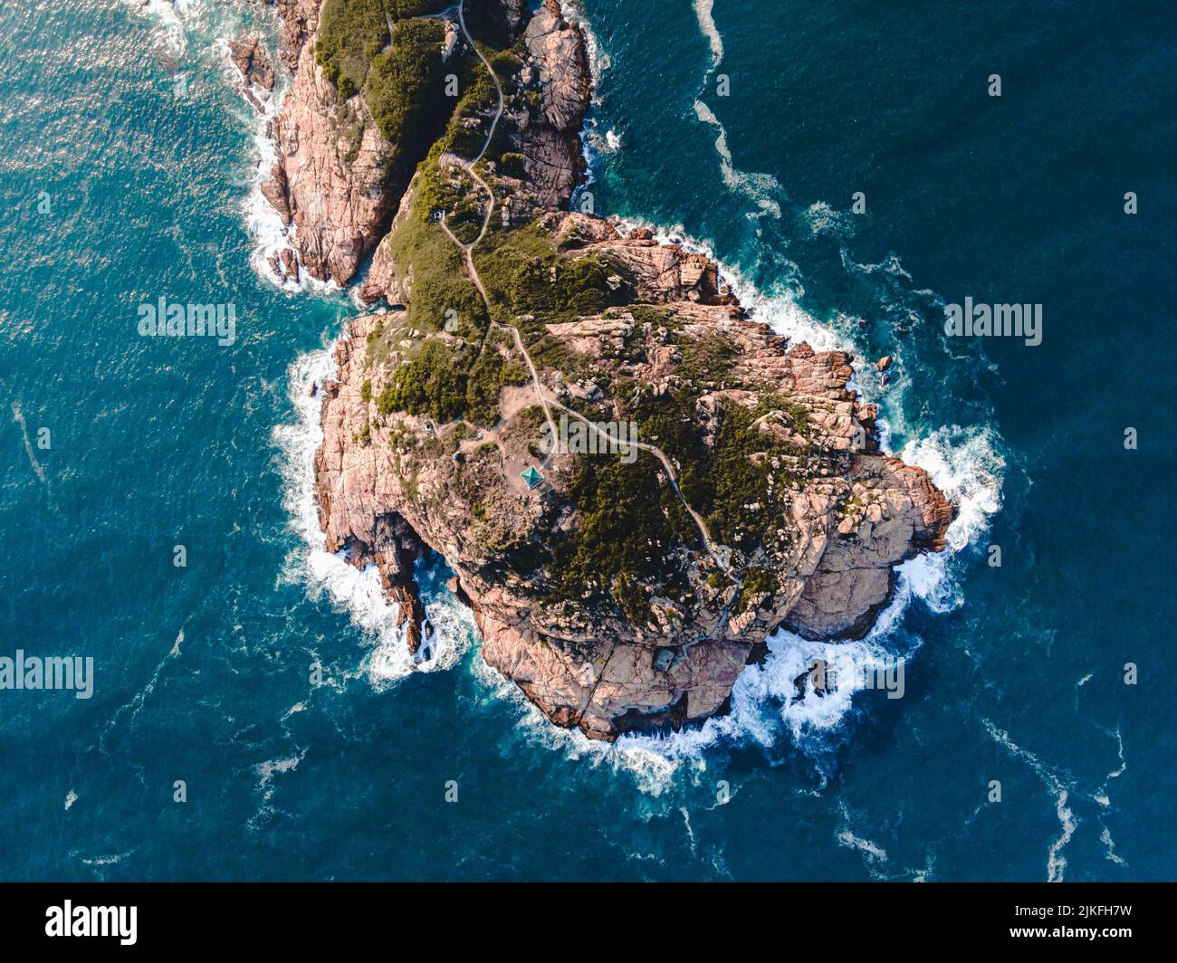 An aerial top view of a rocky Tai Tau Chau island washed by ocean waves ...