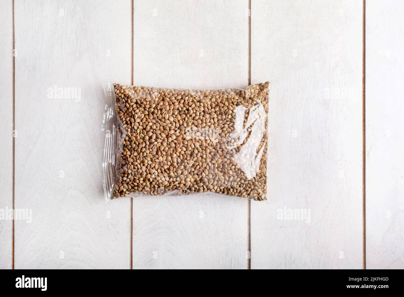 Hemp seeds in transparent packaging on a light wooden background ...