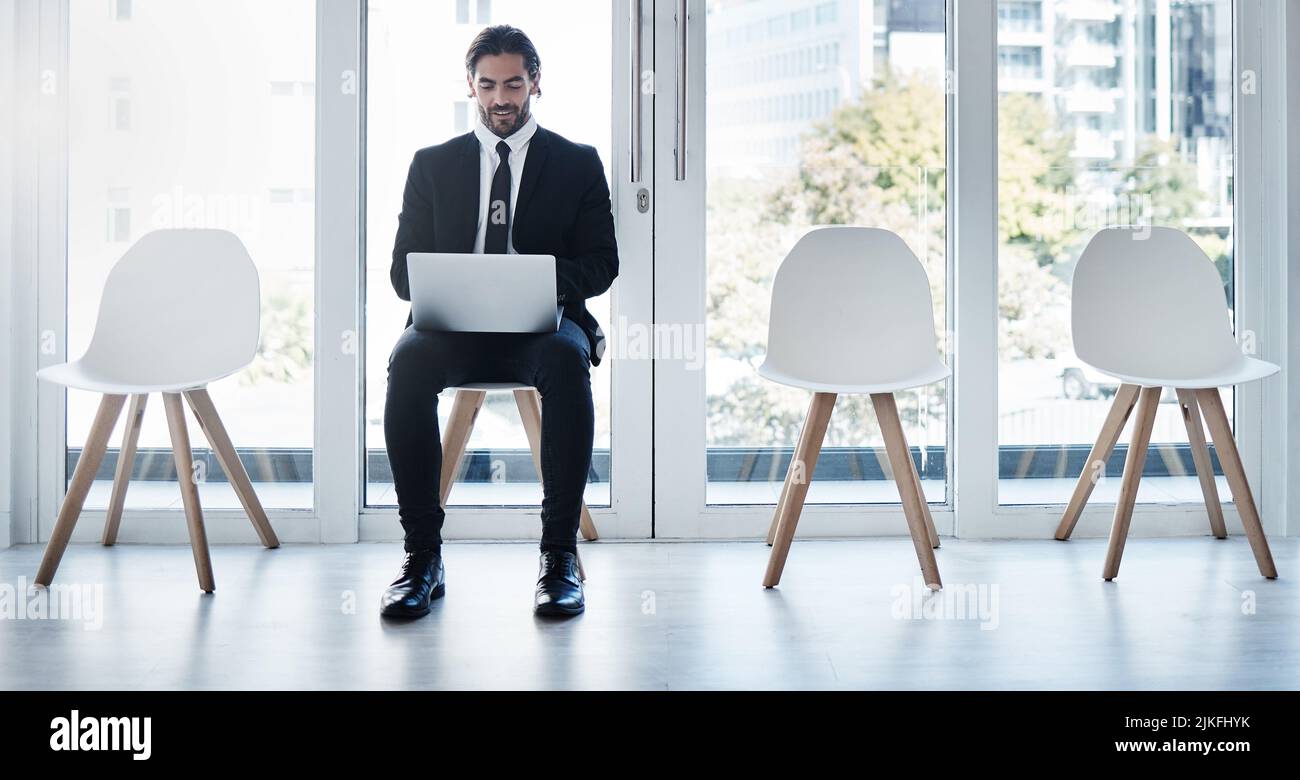 Working while I wait. a young businessman using a laptop while waiting ...