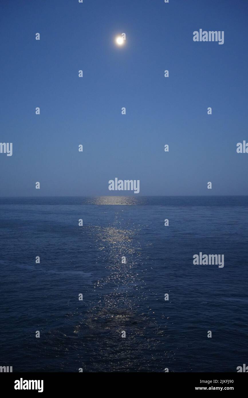 Idyllic view of the sun rising over calm sea and reflecting on its ...