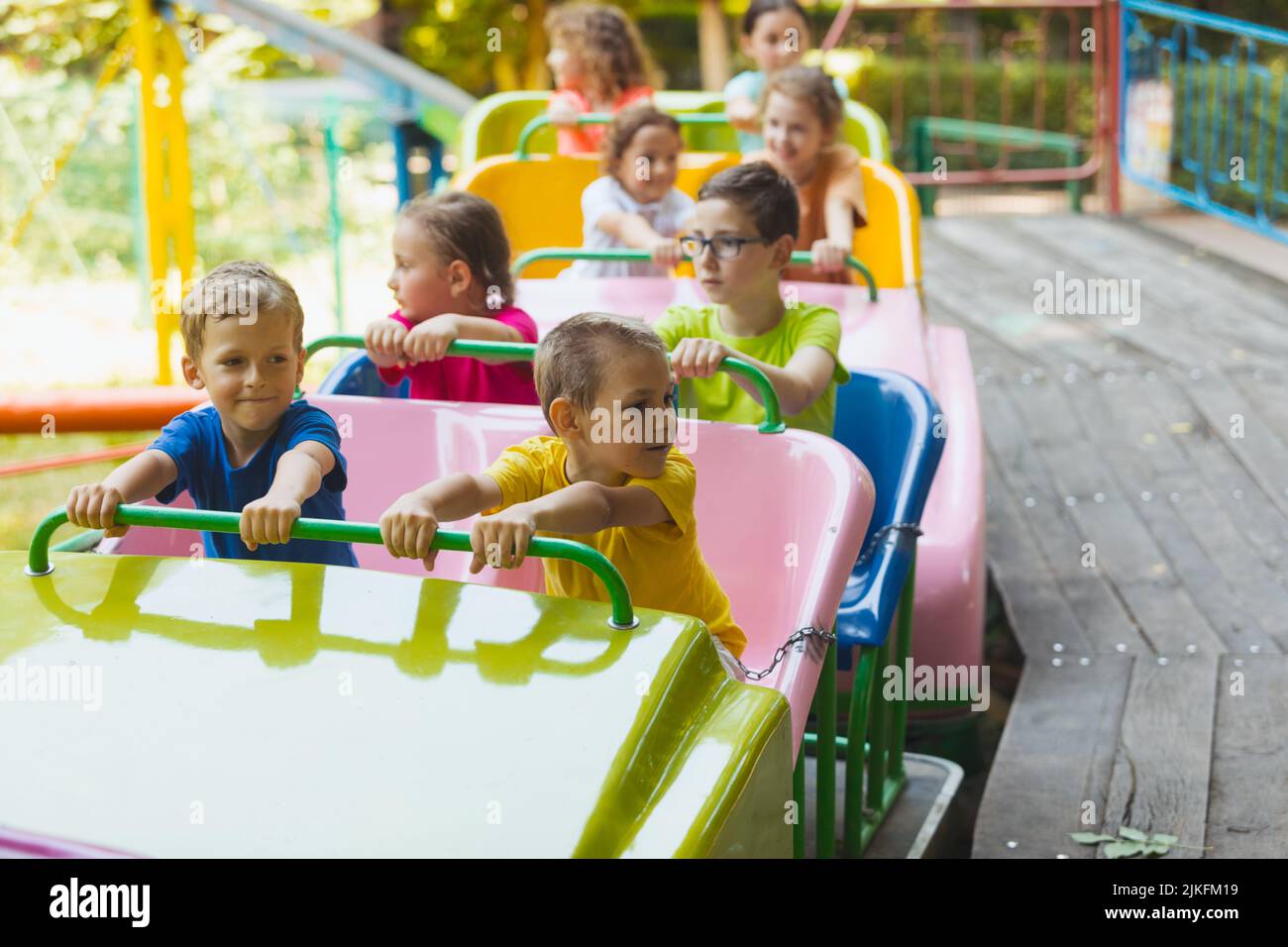 The happy little kids ride on a roller coaster in the amusement park on ...