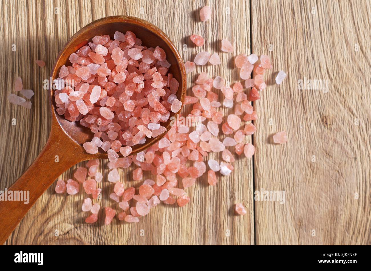 Himalayan pink salt in spoon on a wooden background, top view ...