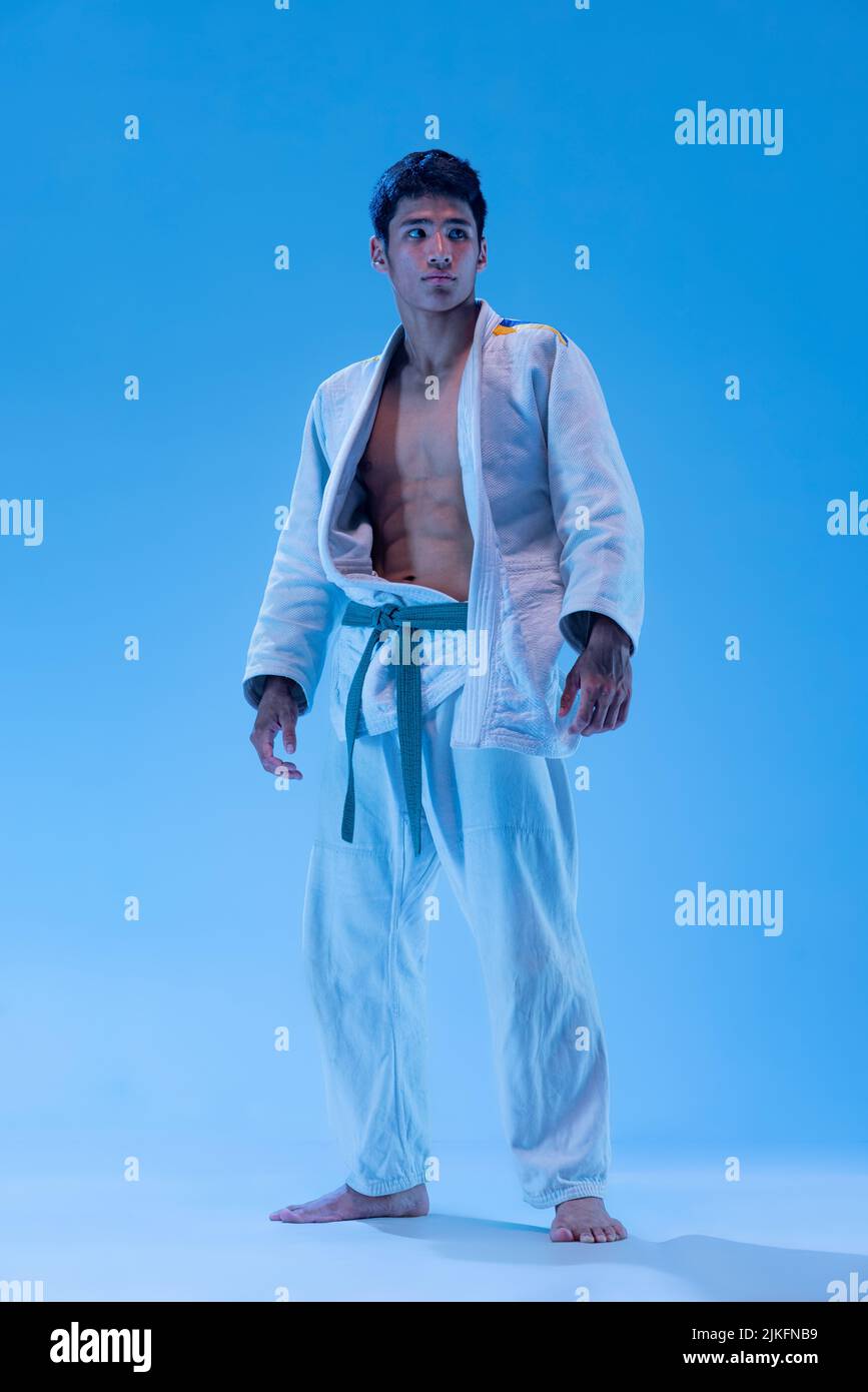 Portrait of young sportive man, judo athlete posing in white kimono ...