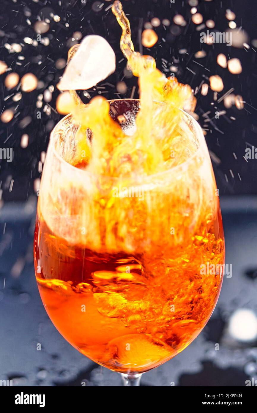A vertical closeup of a glass filled with splashing Spritz Veneziano ...