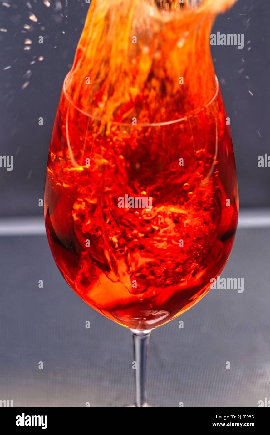 A vertical closeup of a glass filled with splashing Spritz Veneziano ...