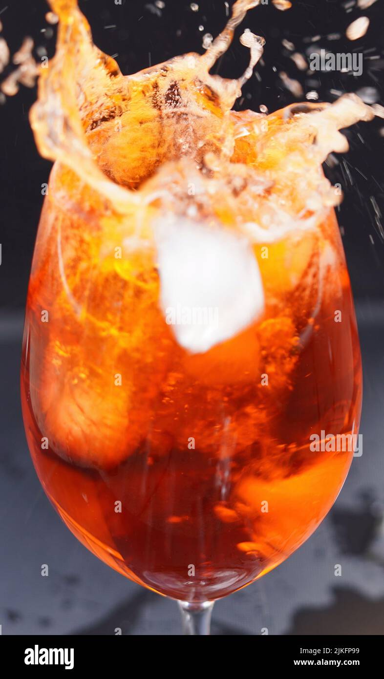 A vertical closeup of a glass filled with splashing Spritz Veneziano ...