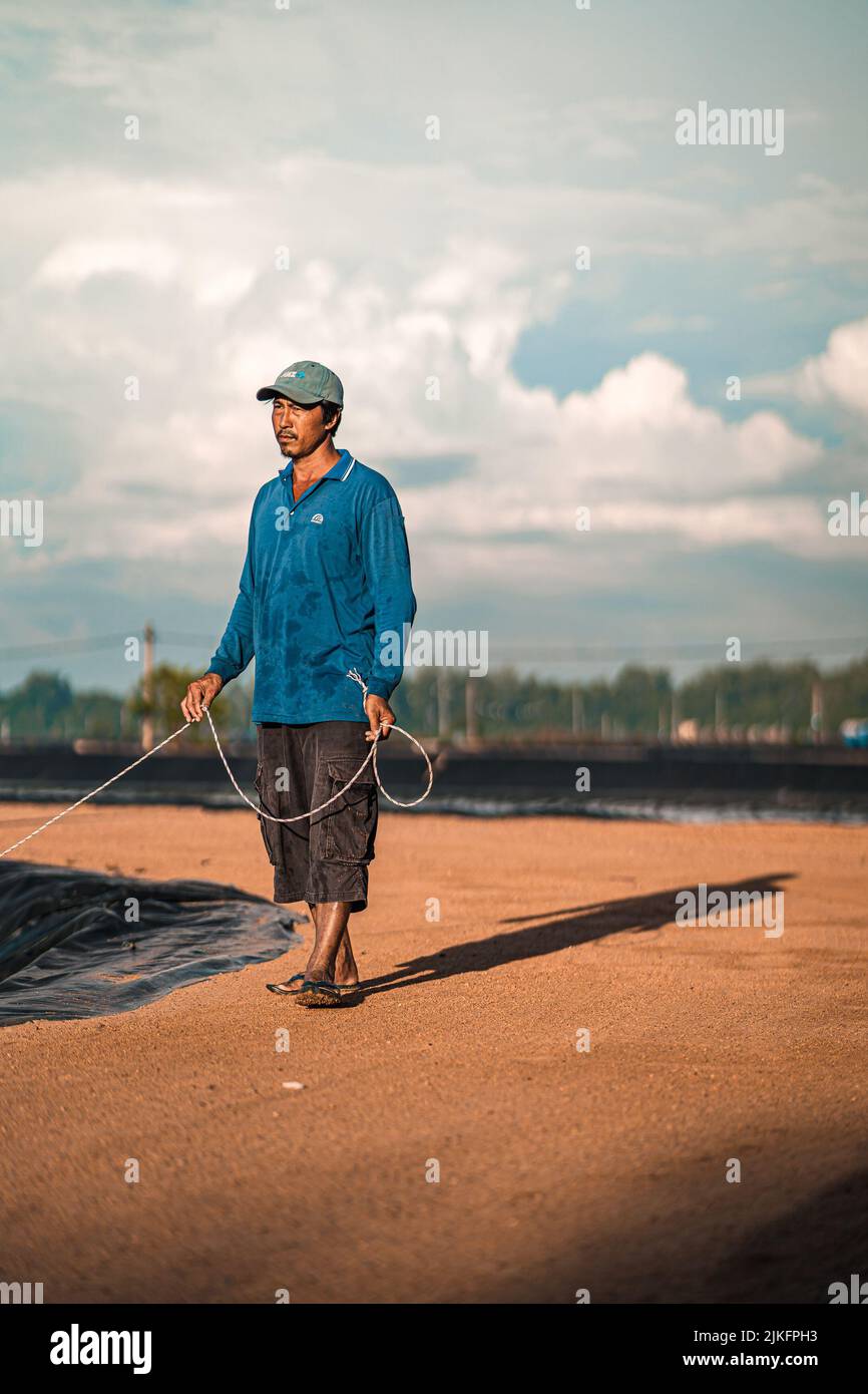 A vertical shot of Malaysian fisherman fishing on the lakeshore Stock ...