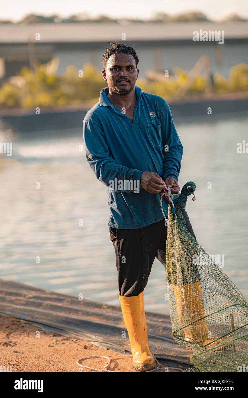 A vertical shot of Malaysian fisherman looking at the camera standing ...