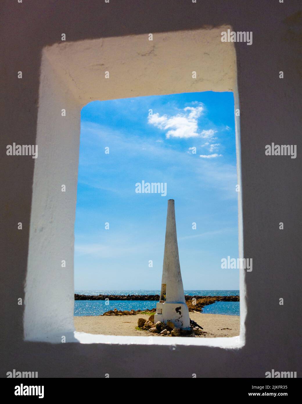 A vertical shot of white obelisk on the beach seen through a ...