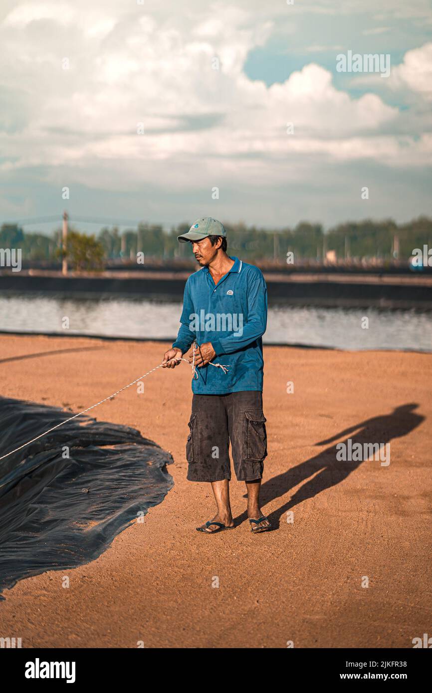 A vertical shot of Malaysian fisherman fishing on the lakeshore Stock ...