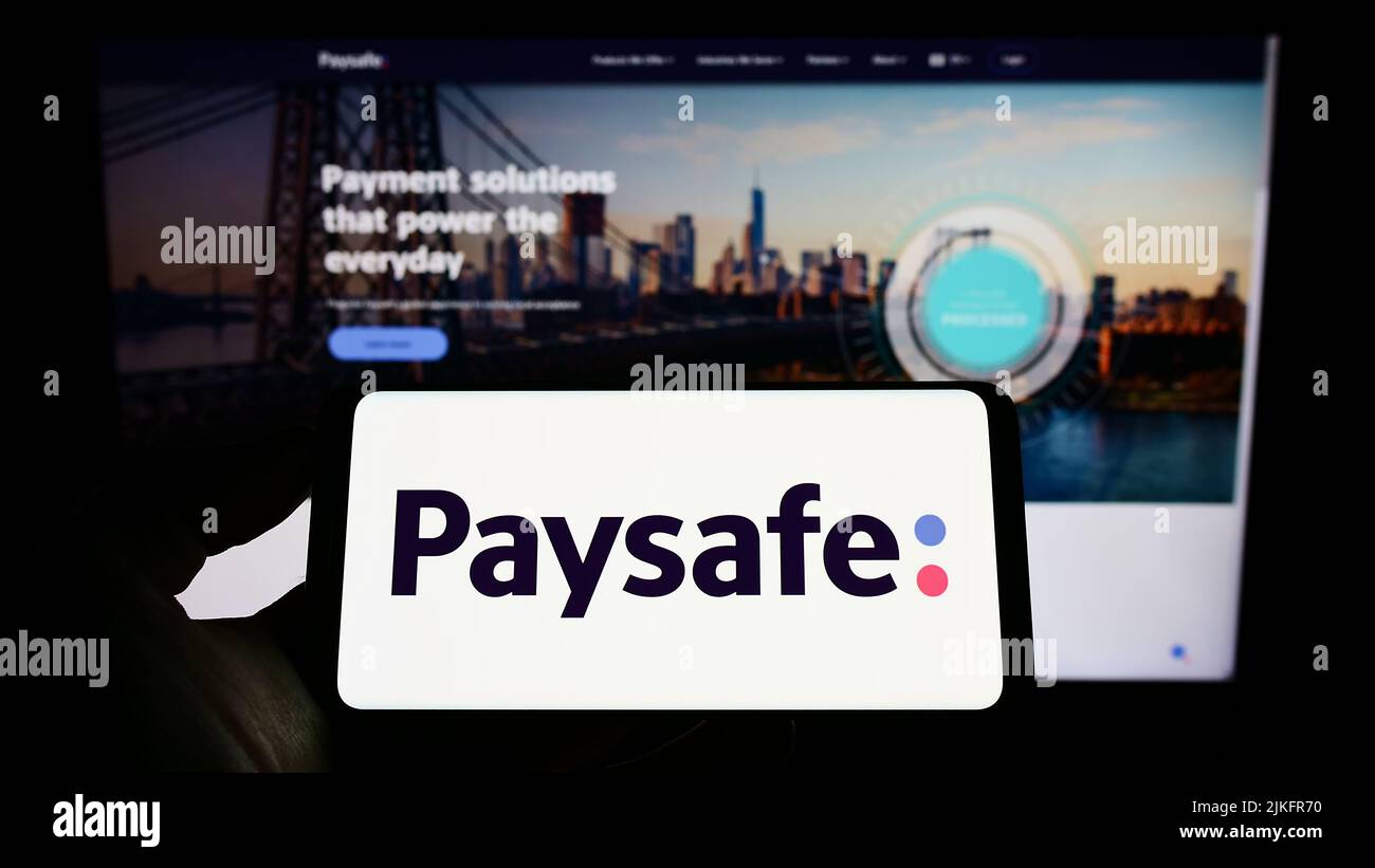 Person holding cellphone with logo of British payments company Paysafe ...