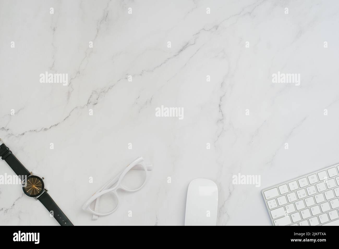 Marble desktop with keyboard, glasses, wristwatch and mouse. Copy space ...