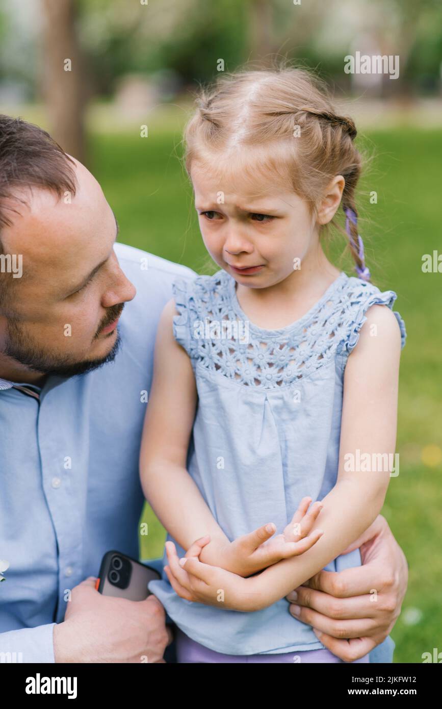 Dad comforts crying daughter on a walk in the park Stock Photo - Alamy