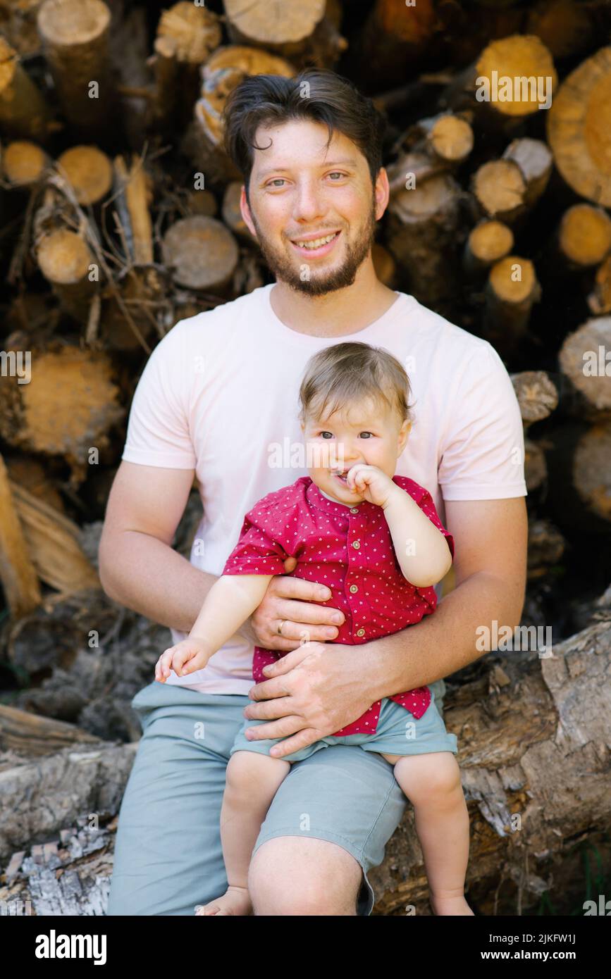 A happy father and his son are sitting on logs in the forest. Happy ...