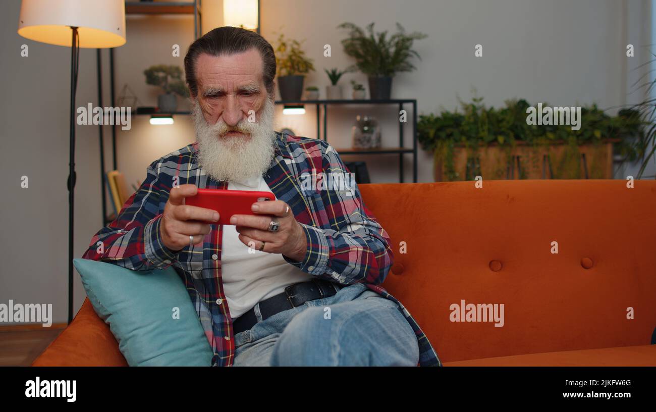Worried senior old grandfather man enthusiastically playing racing ...
