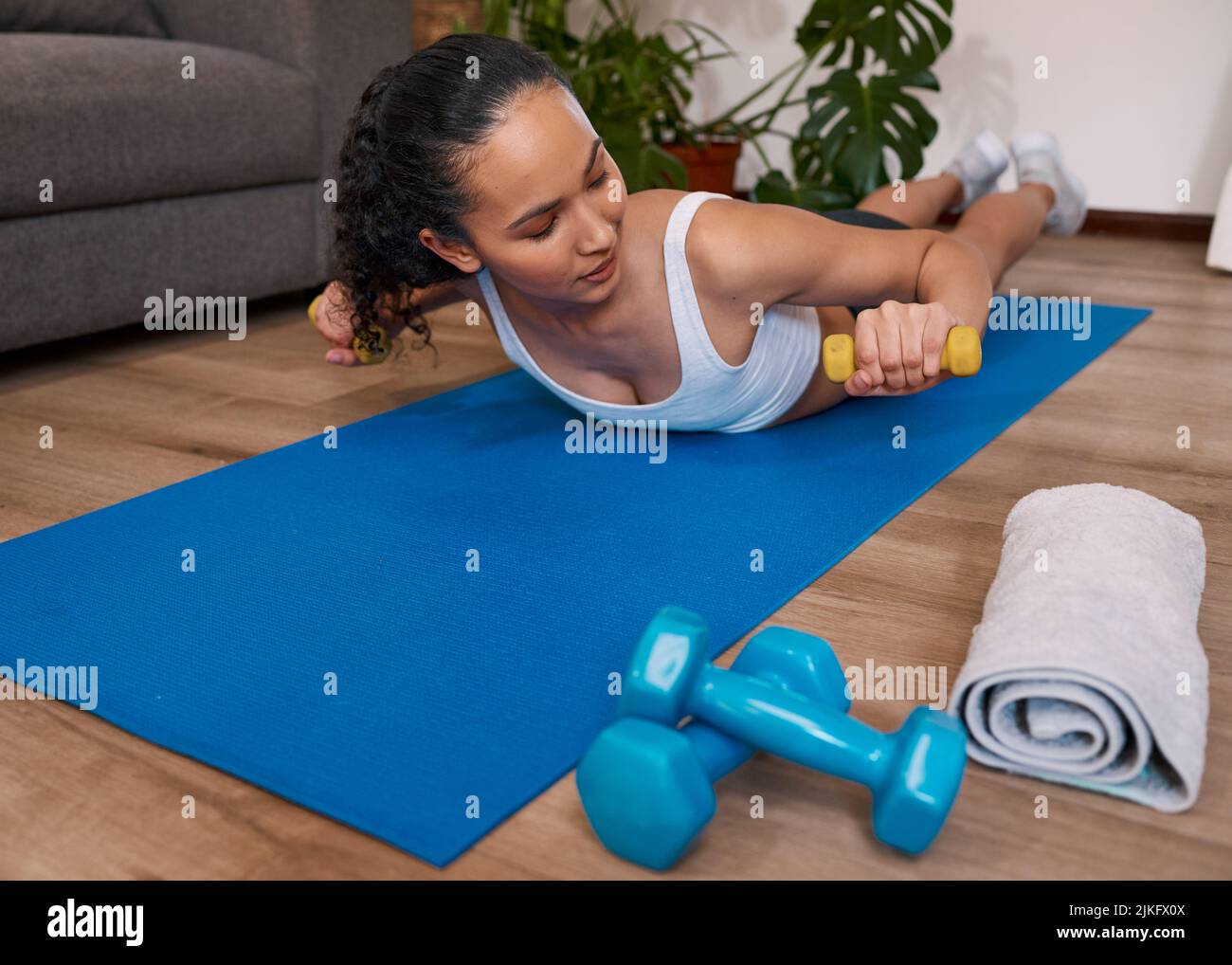 A young multi-ethnic woman uses weights during floor workout Stock ...