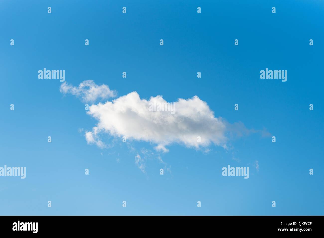 Bright blue summer sky with a white fluffy cloud photographed in the centre Stock Photo - Alamy