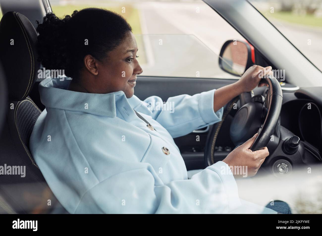 Side view portrait of young black woman driving car behind window, copy ...