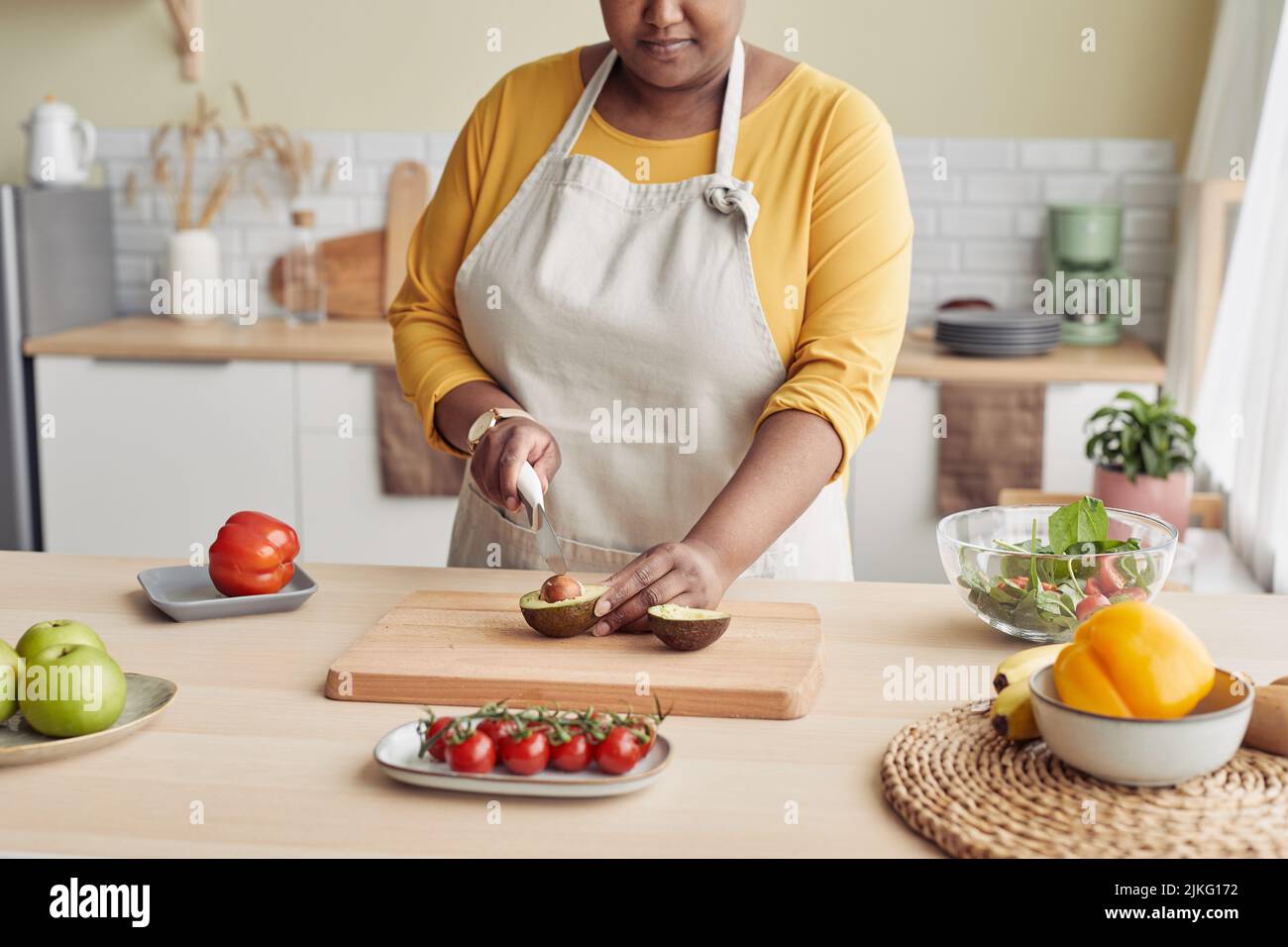 Cropped portrait of black woman cutting avocado while cooking healthy ...