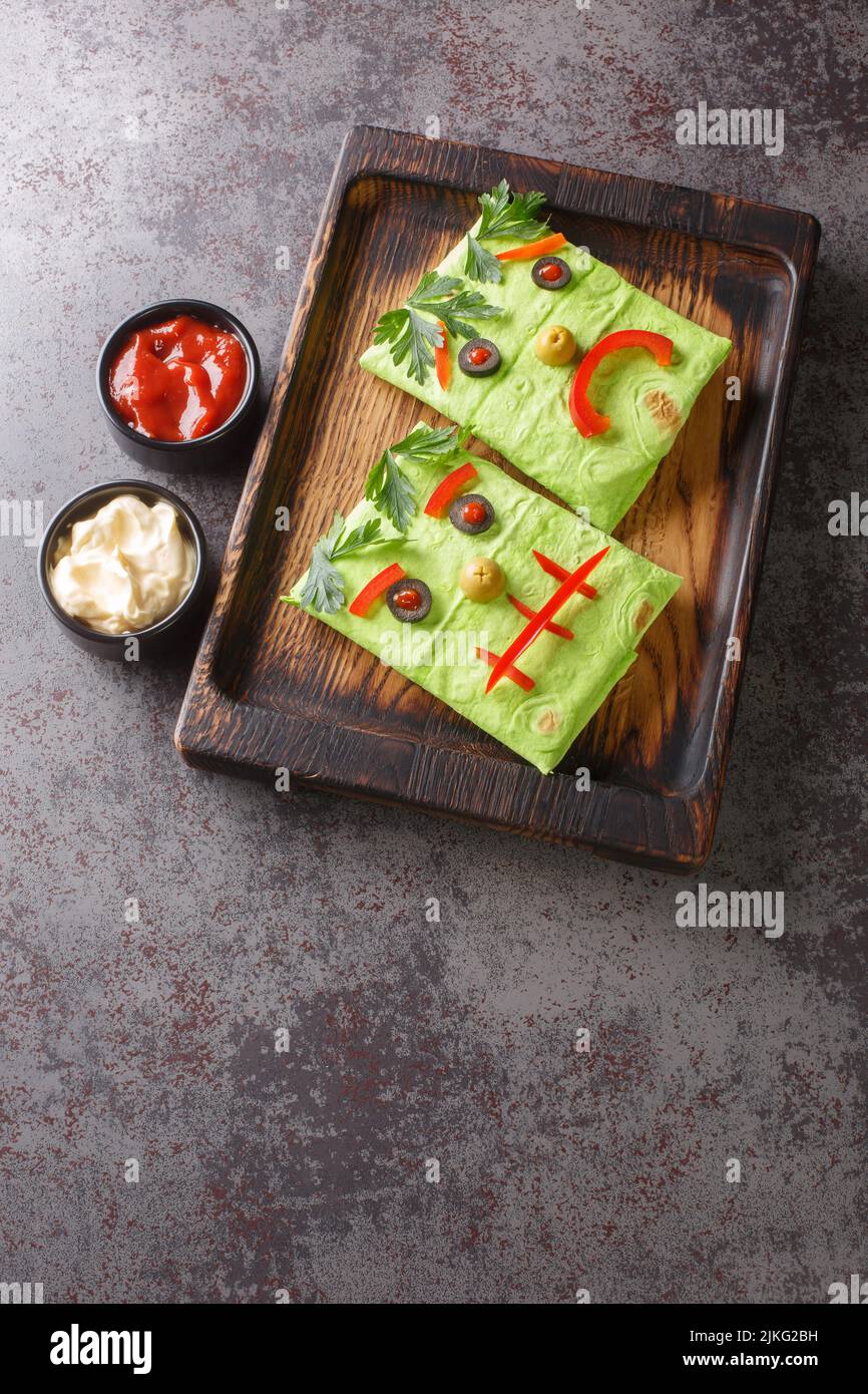 Funny kids burrito monster with sauces on a wooden tray on the table ...