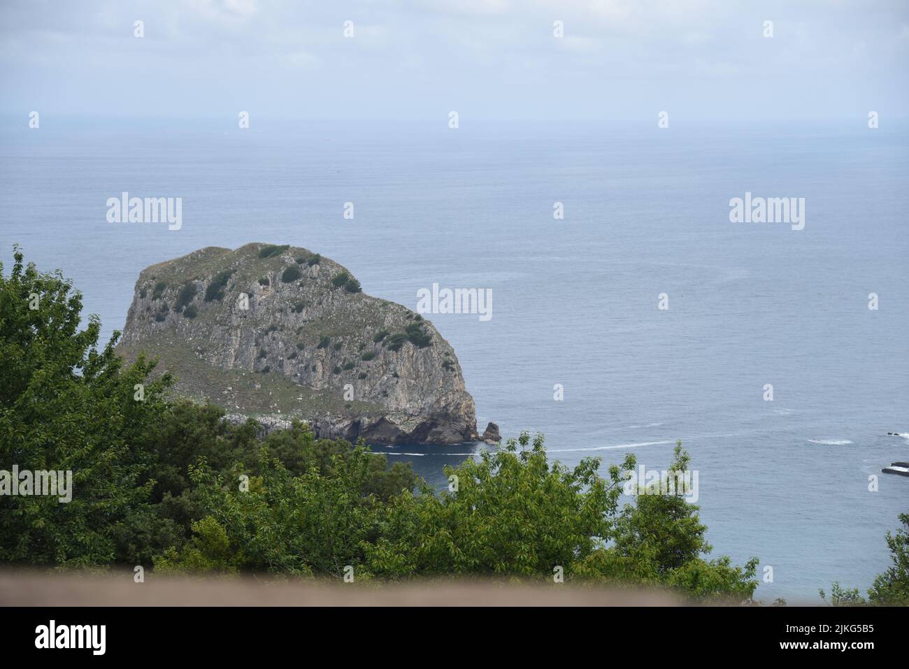 An aerial view of giant rock formation in the sea with green trees in ...