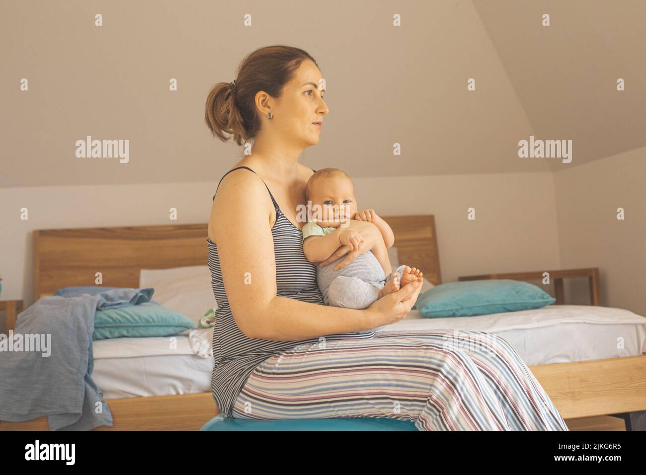 Mother holding and rocking baby sitting on fitball Stock Photo - Alamy