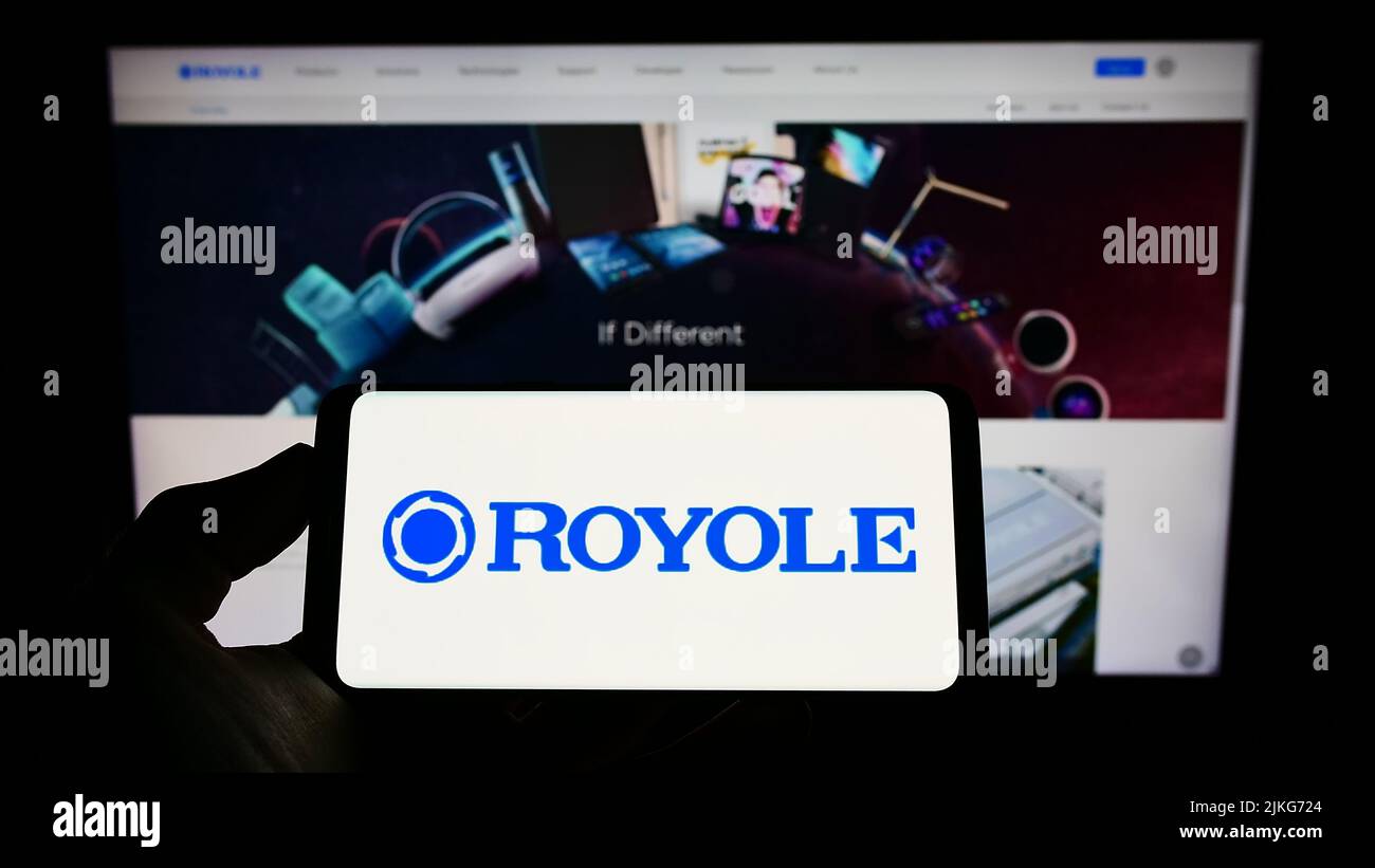 Person holding cellphone with logo of display manufacturing company ...