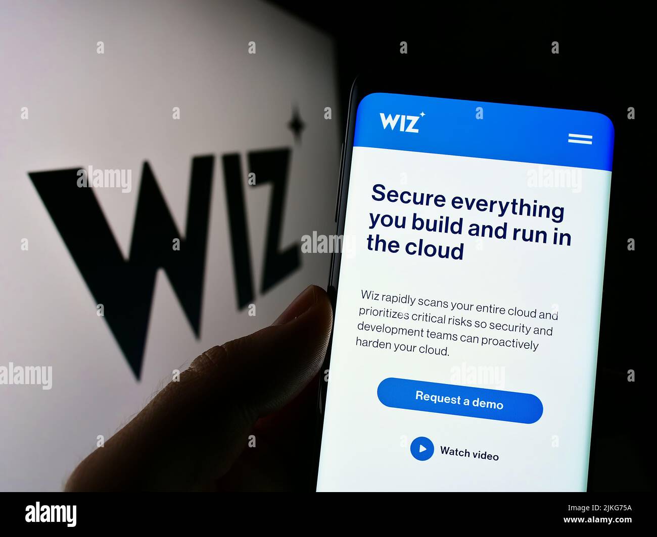 Person holding cellphone with webpage of US cloud security company Wiz Inc. on screen in front ...
