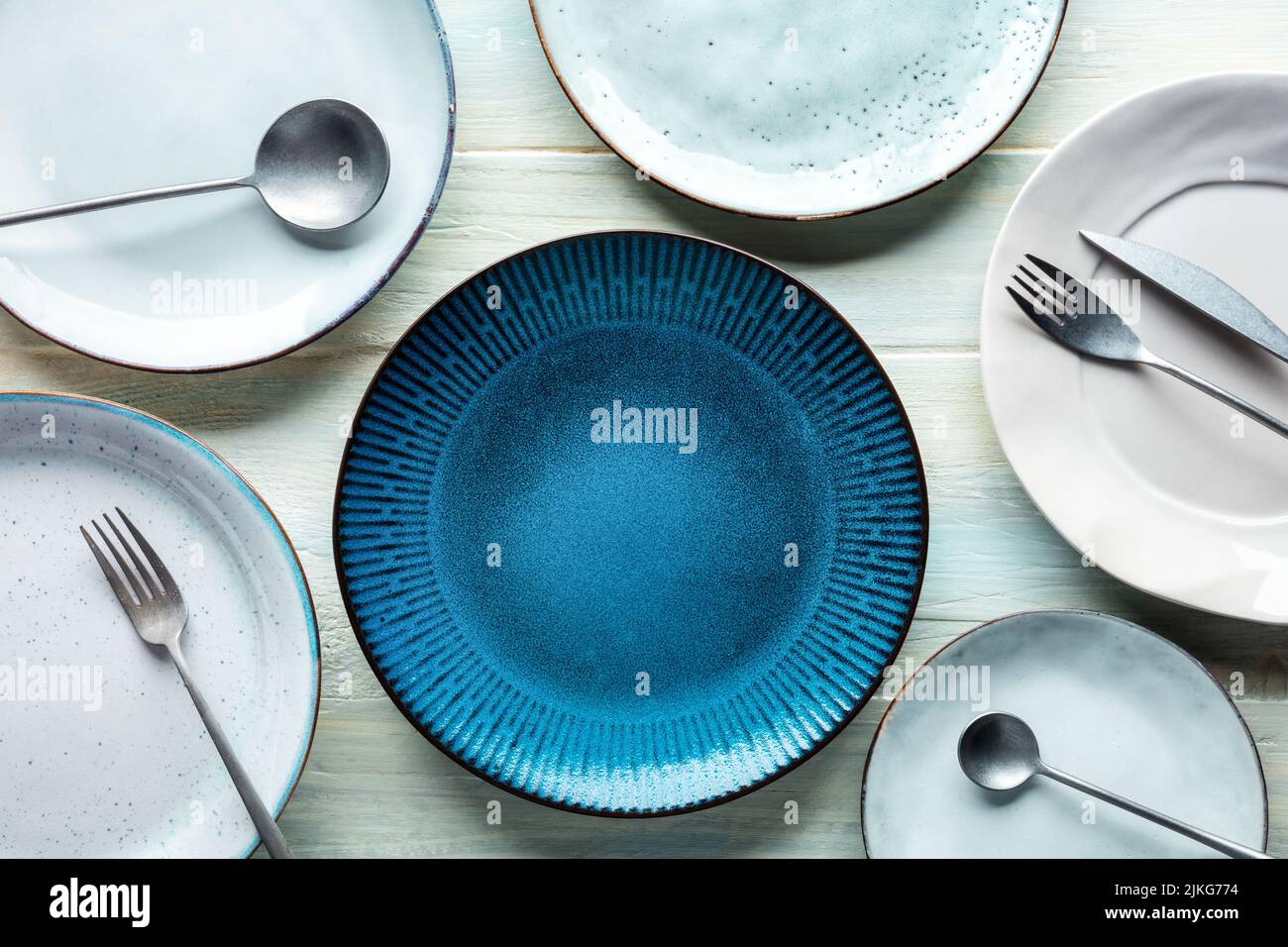 Modern tableware set with cutlery and a vibrant blue plate, overhead ...