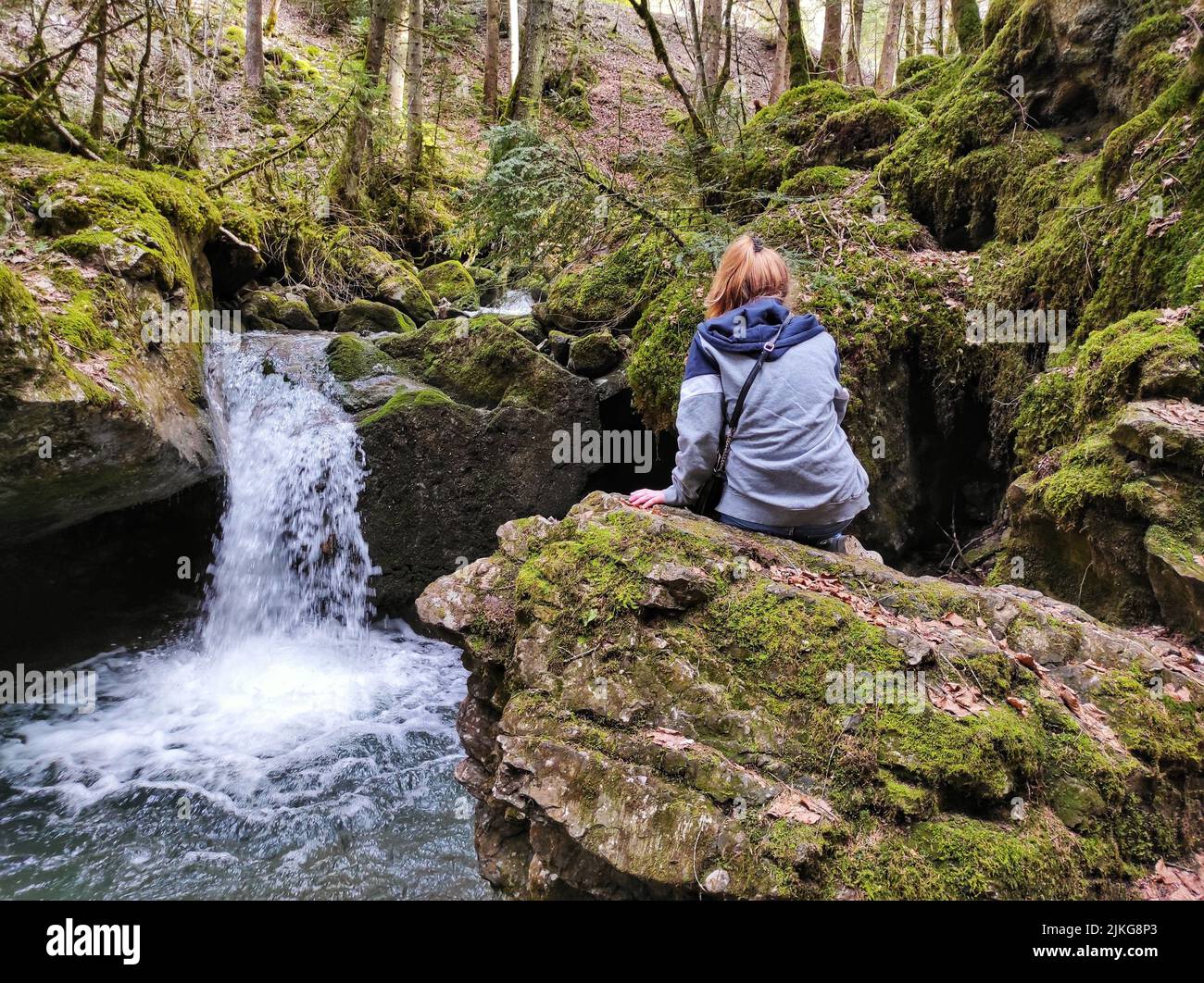 A tourist sitting by the waterfall Stock Photo - Alamy