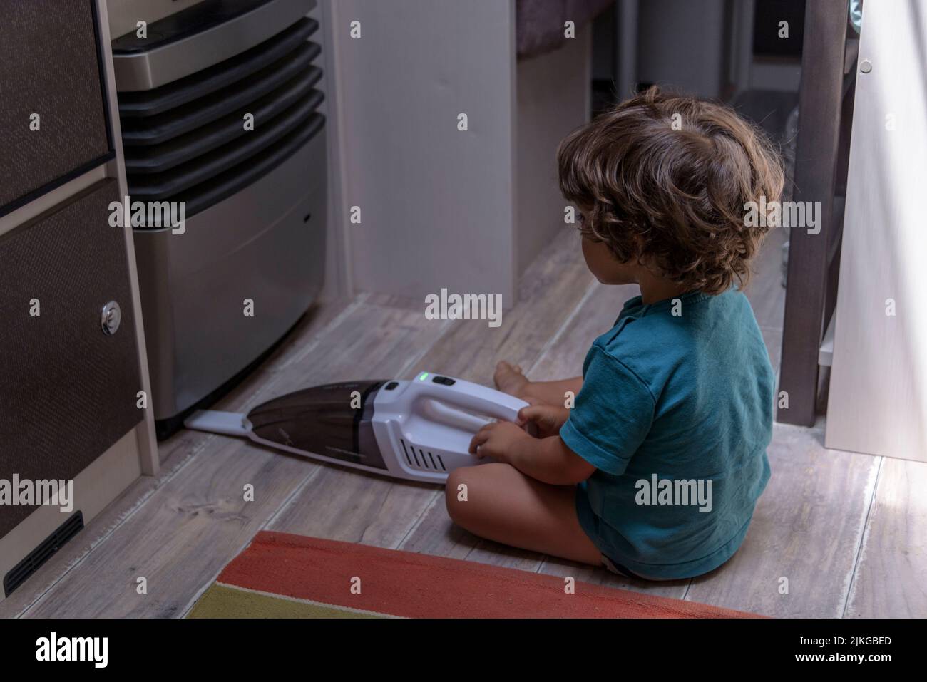 A sweet little boy vacuums the caravan while on vacation. A cute boy is ...