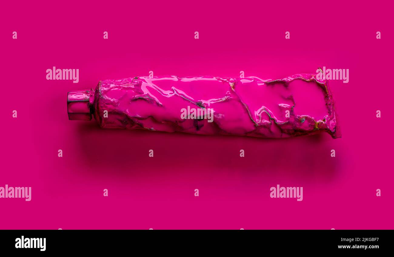 Tube of magenta oil paint on a plain magenta background also with ...