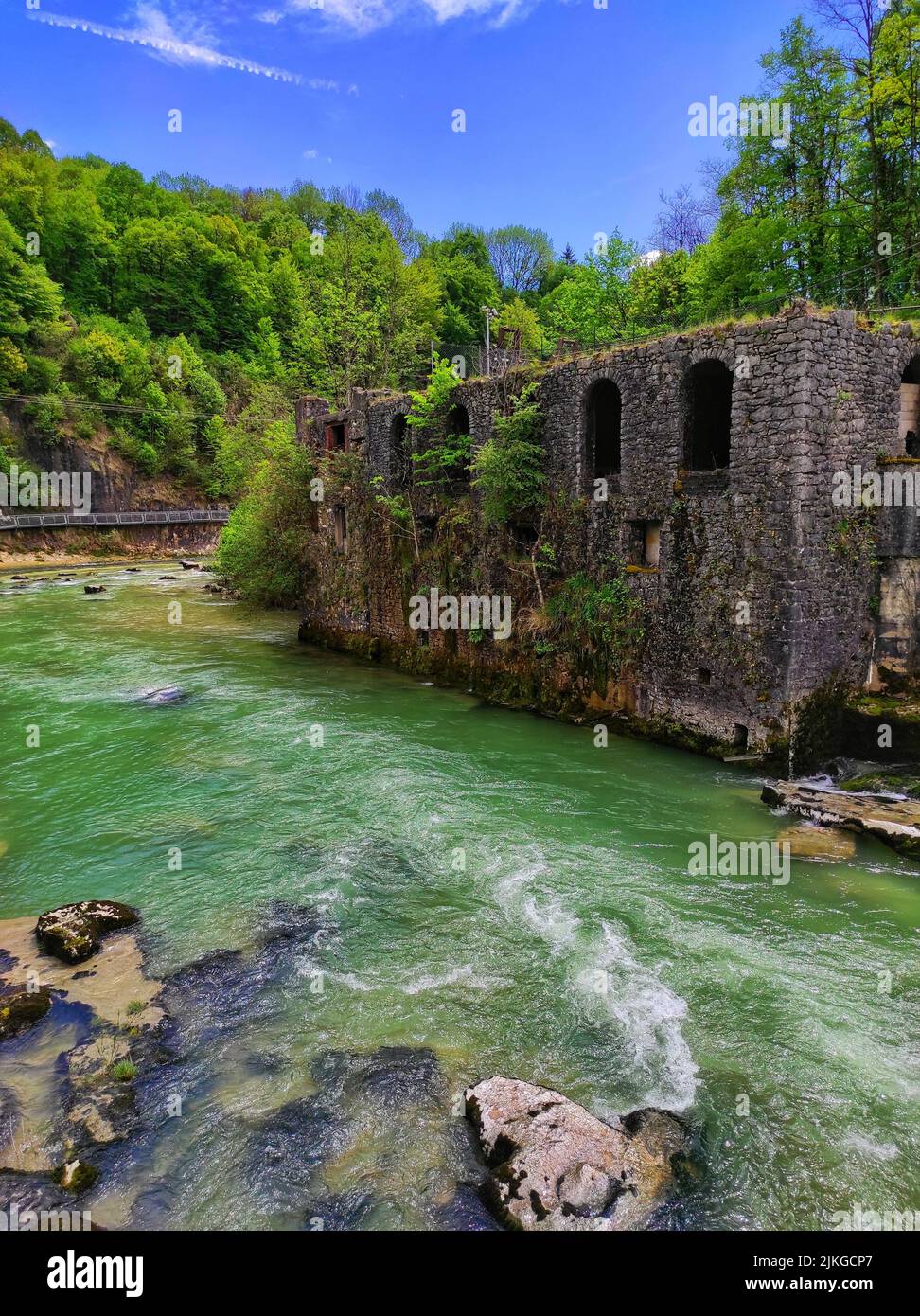 A vertical shot of a stone ruins of old factory along river in french ...