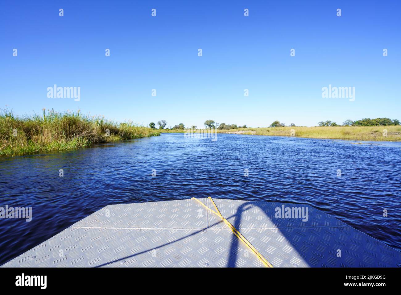 Small safari boat cruising the waters of the Kwando River. Bwabwata ...