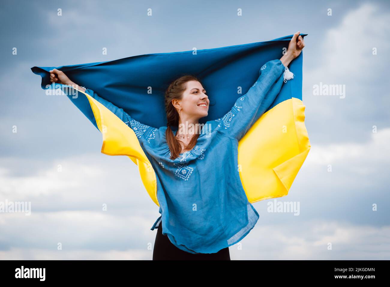 Happy free ukrainian woman with national flag on dramatic sky ...