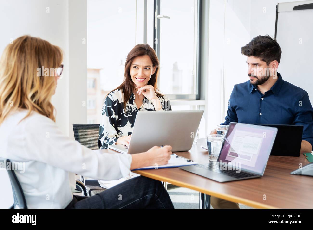 Business people sitting around desk and working together during ...