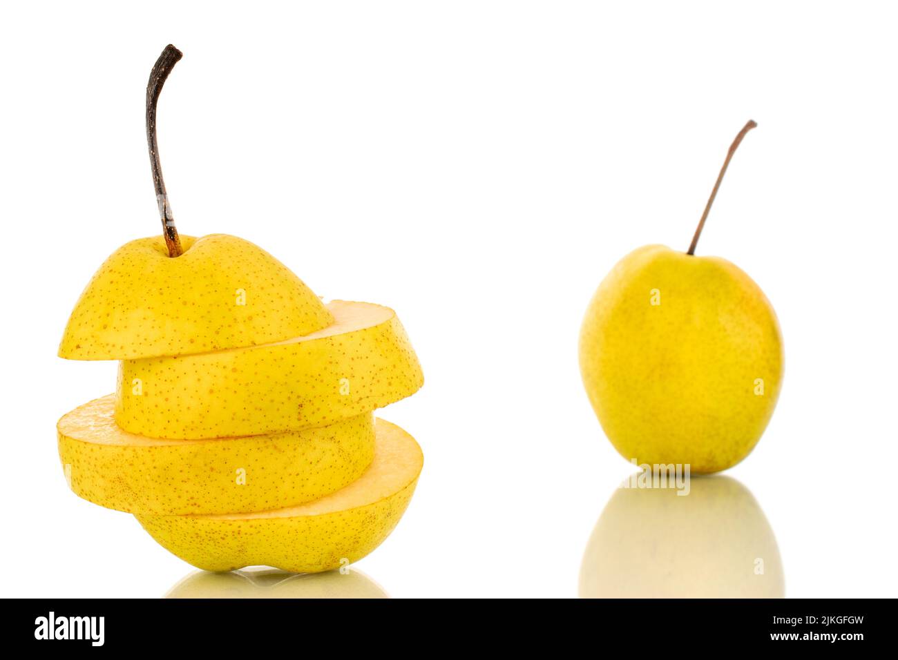 One juicy yellow pear cut into quarters and one whole pear, close-up ...