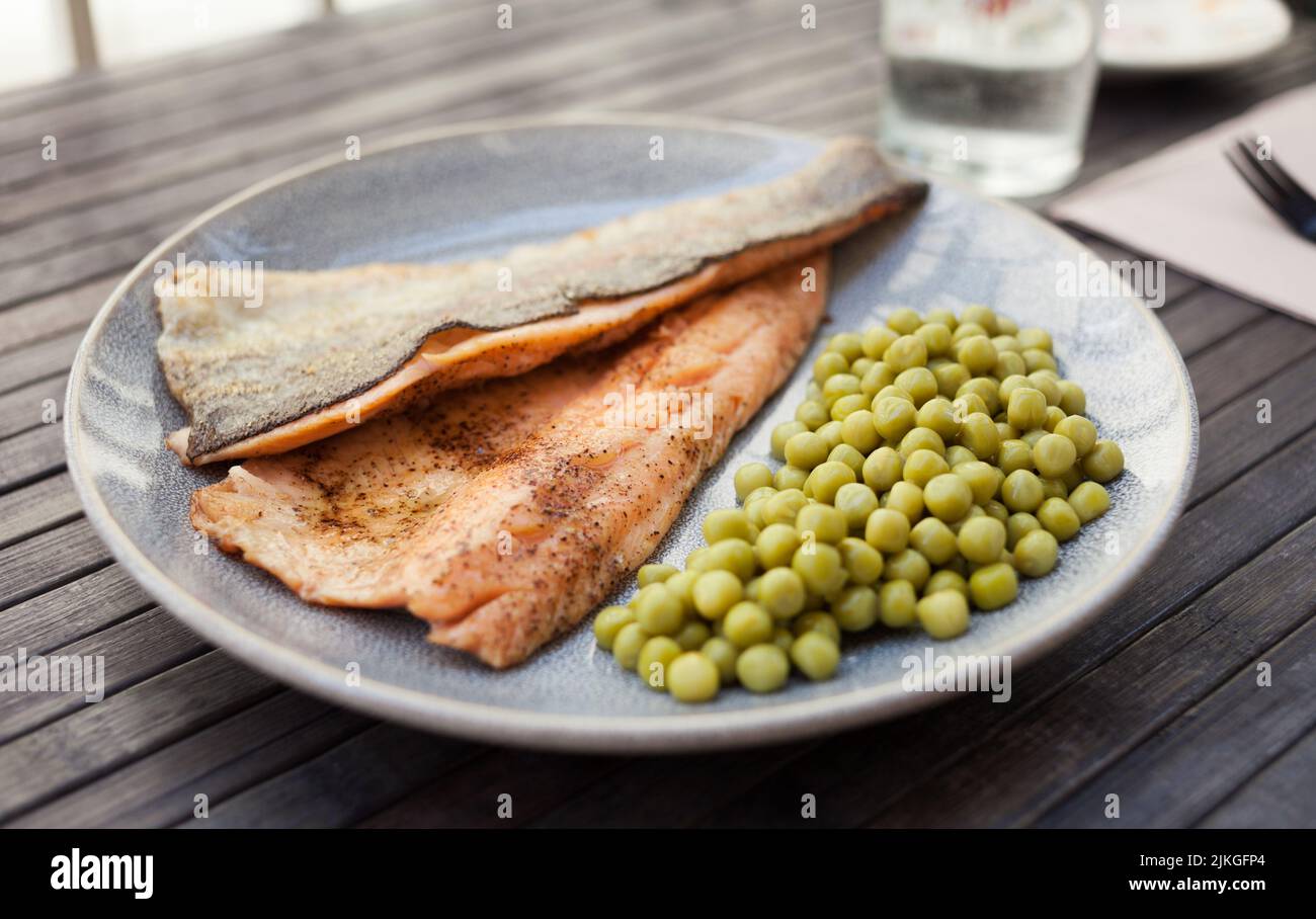 Fried trout fillets served with green peas Stock Photo - Alamy
