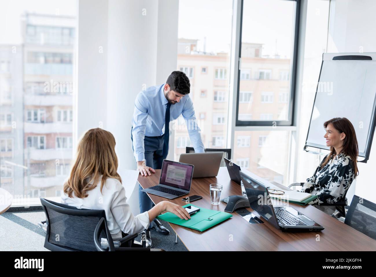 Business people sitting around desk and working together during ...