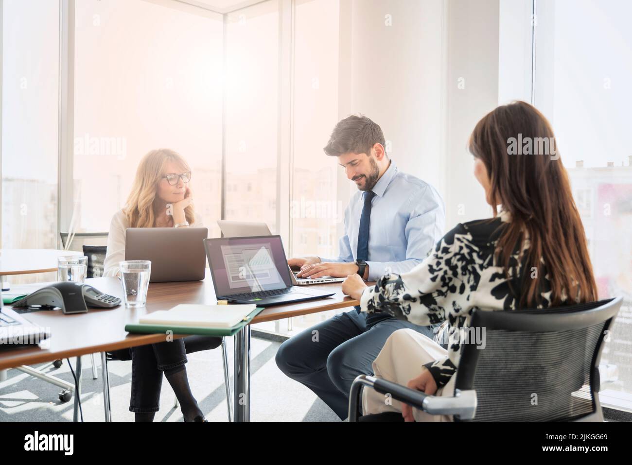 Business people sitting around desk and working together during ...