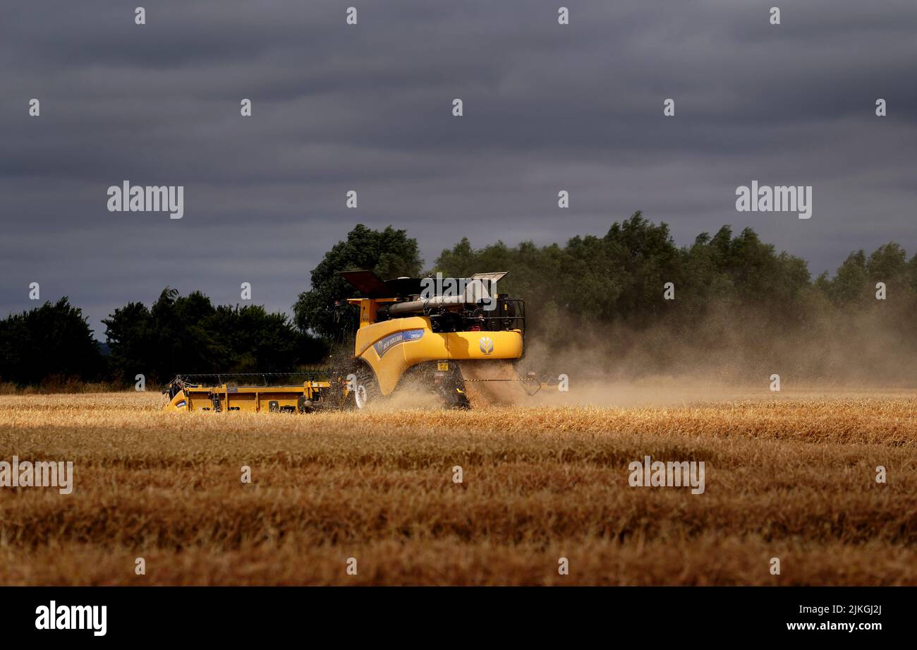 A combine harvester at work in a field near Brenzett in Kent, as the ...